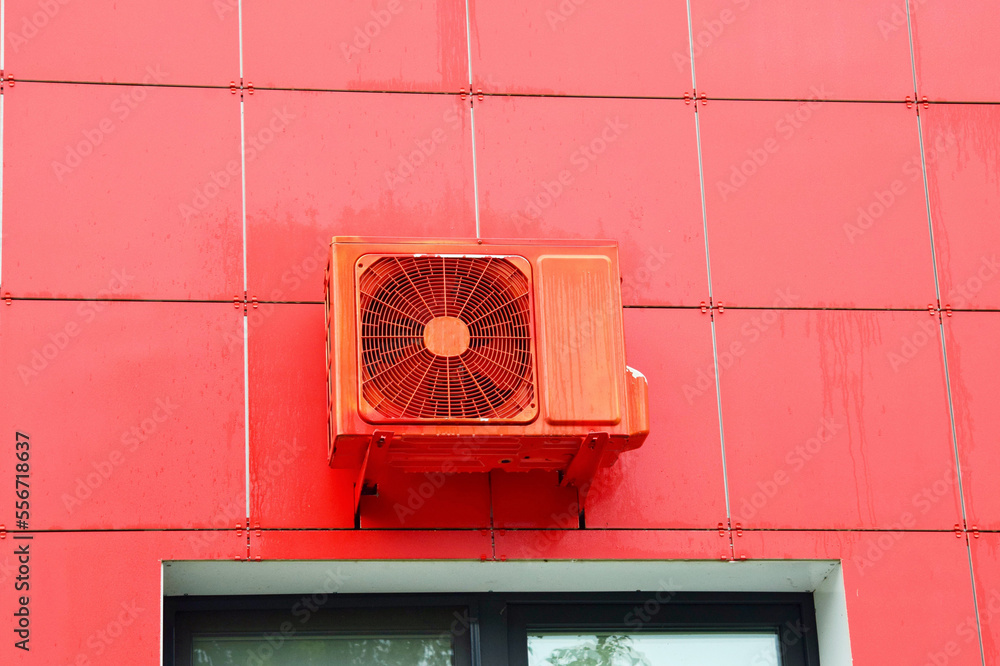 Red color air conditioner hanging on the wall of modern building in red ...