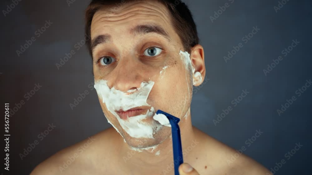 A guy of European appearance, a bearded handsome man shaves with a ...