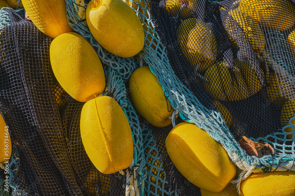 Pile of multi-colored fishing nets with yellow floats dry on the pier ...