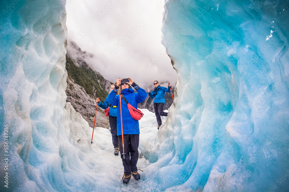 Travelers exploring the famous Franz Josef Glacier with its, blue ice ...