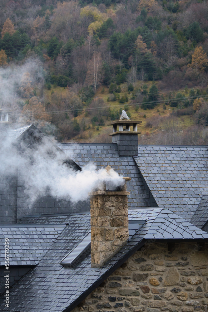 Pequeña casa europea con una chimenea humeante. Humo desde una chimenea ...