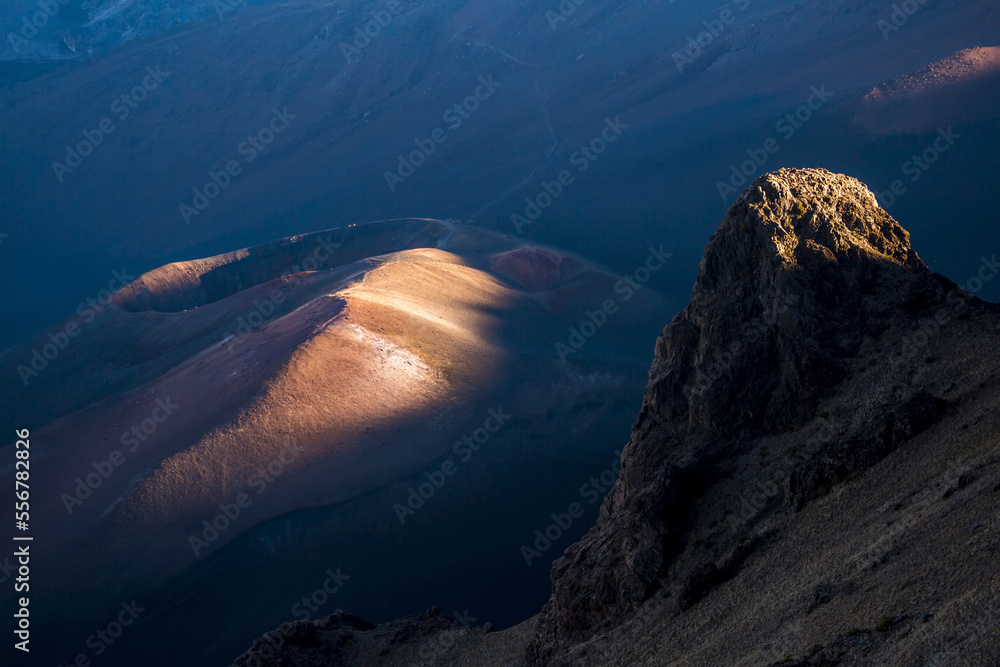 Sunlit tips of a volcanic rock formation and the Haleakala Crater at ...