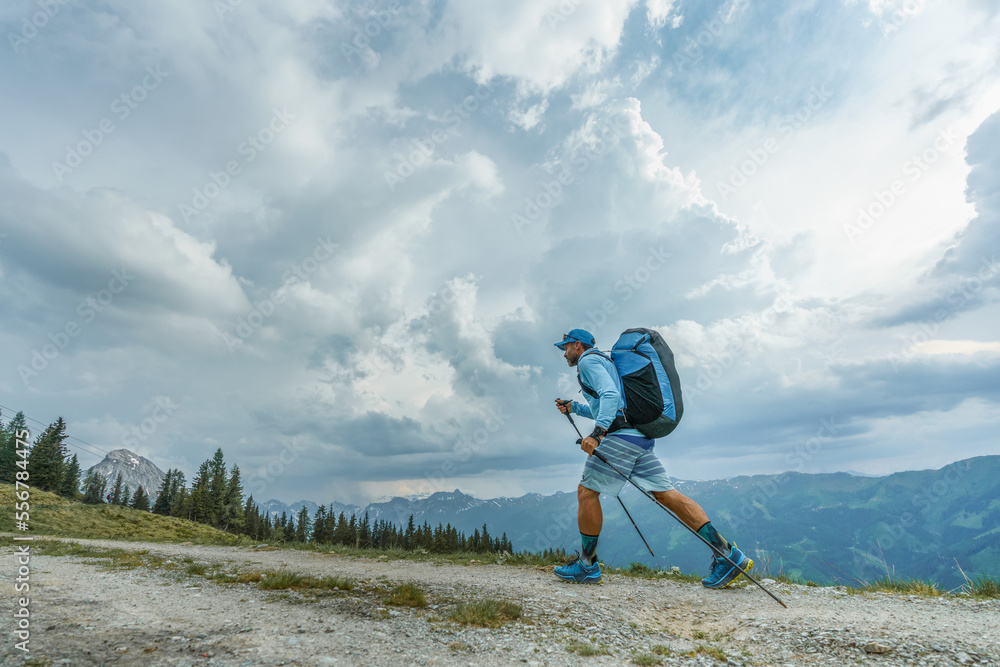 An athlete in the Redbull X Alps, a paragliding race, hikes with ...