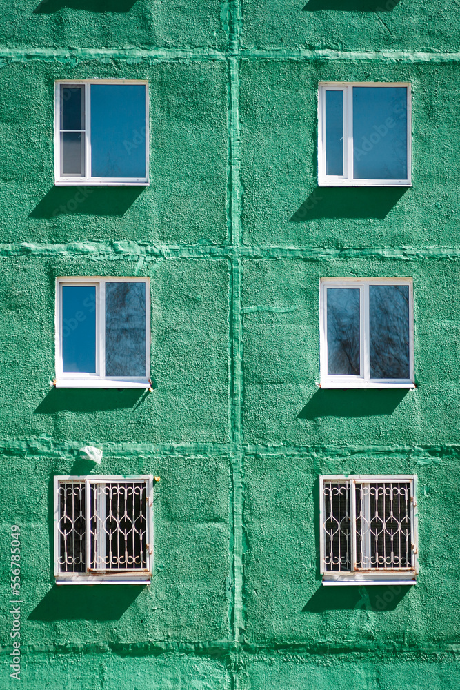 Facade of a green building with white windows on a bright sunny day ...