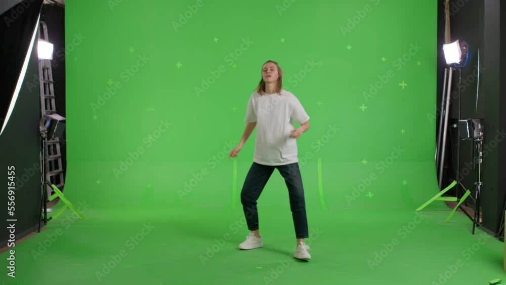 Young woman dancing on a green screen background. Girl makes a gesture ...