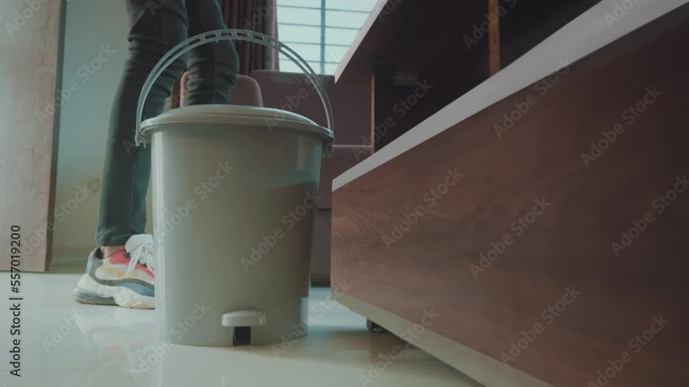 Young college boy enters inside the room puts dustbin box on the floor ...