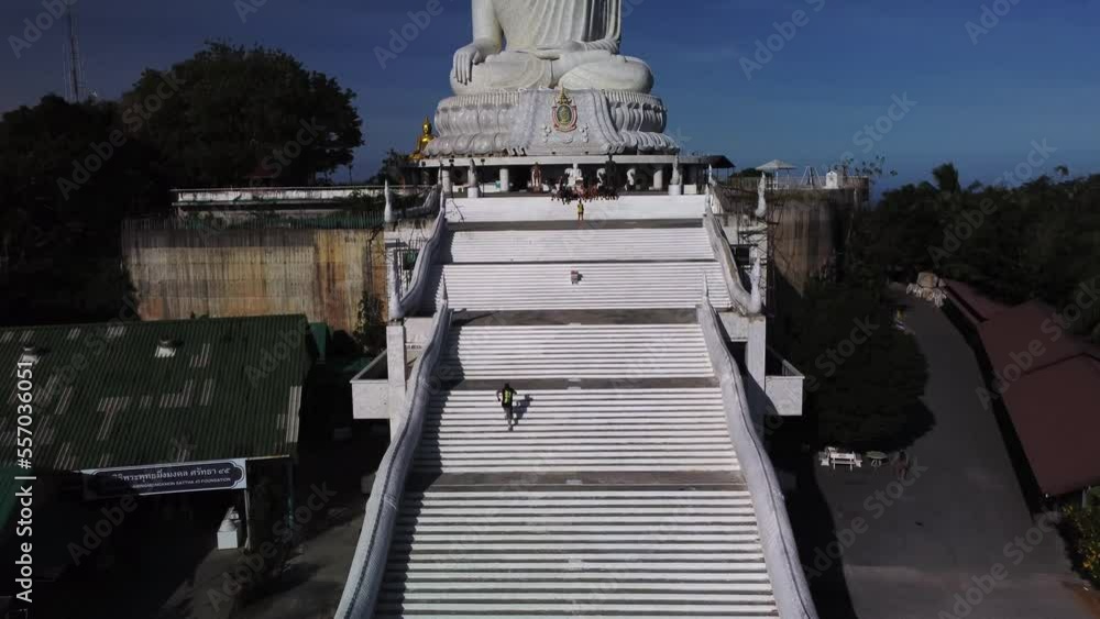 Man is running up on stairs leading to huge temple with Buddha statue ...