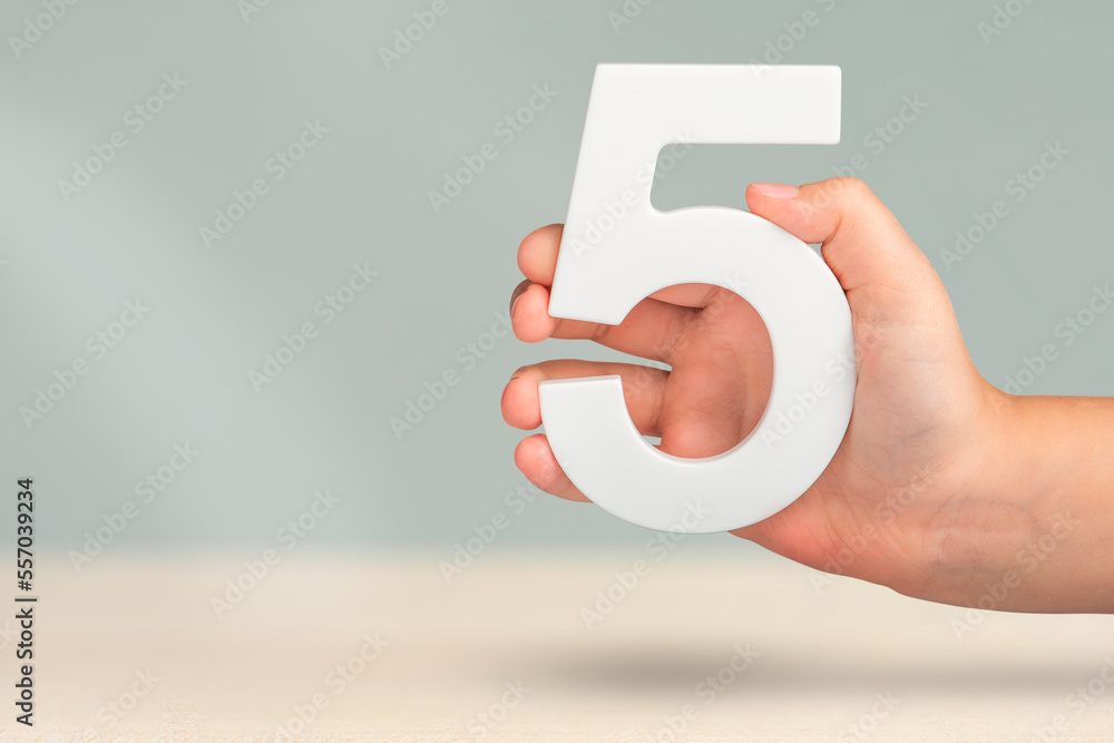 Number five in hand. Hand holding white number 5 on blurred background ...