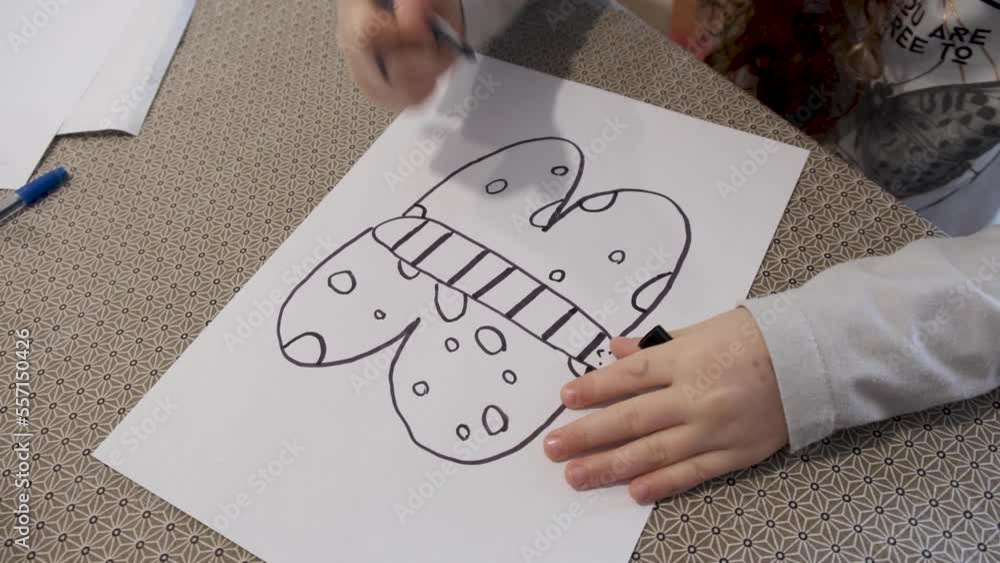 Child with marker drawing a butterfly outlines. Kids art. Little girl ...