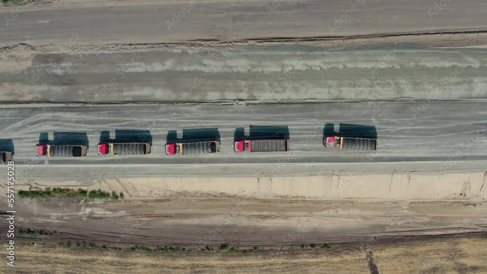 Convoy of red trucks with awnings stands along the road with cargo - an ...