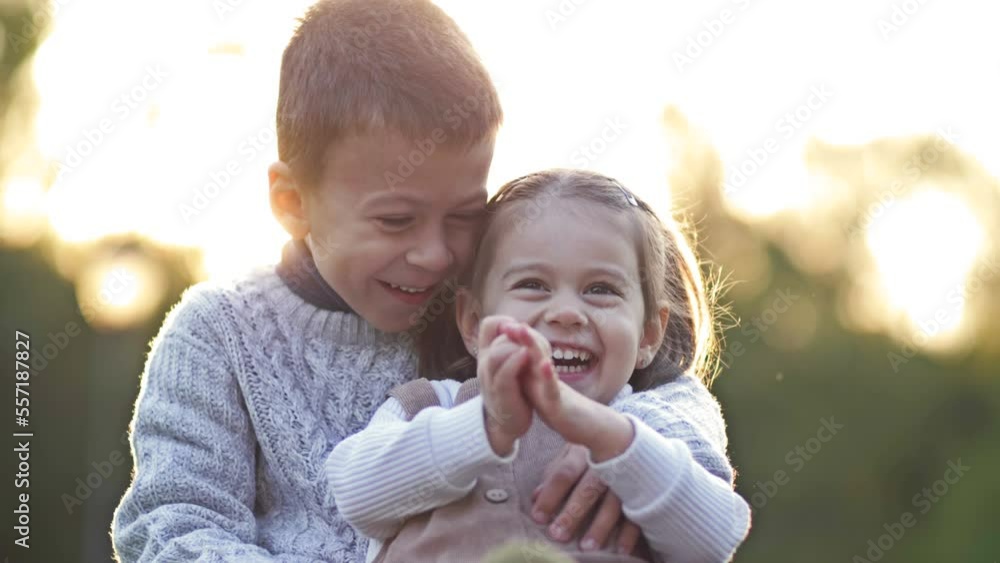 Boy gives his little sister a gentle hug and a girl playfully touches ...