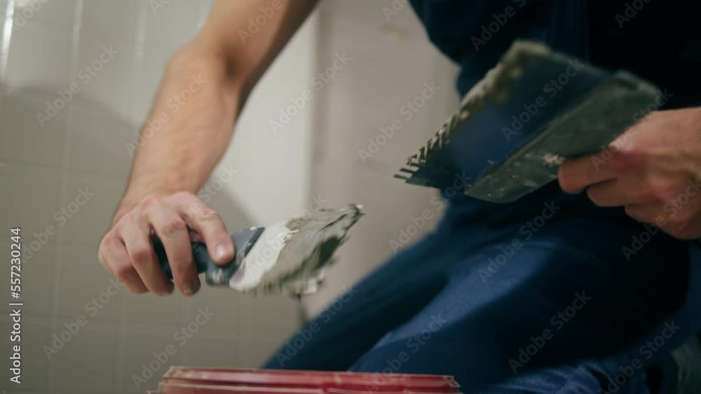 Builder laying tiles using cement and spatula, man installing ceramic ...