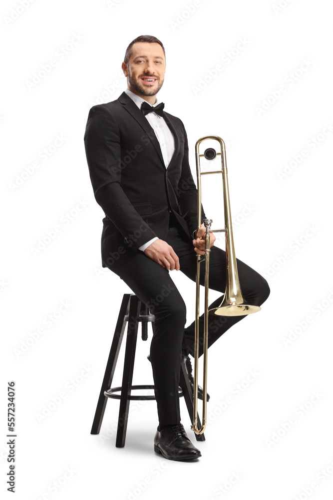 Male musician in a black suit and bow-tie sitting on a chair with a ...