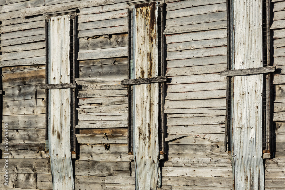 Old wooden siding of a historic structure with its windows covered ...