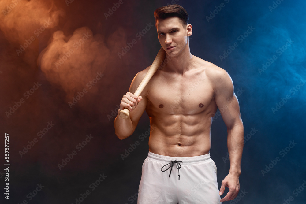 Strong and fit man bodybuilder with baseball bat posing with naked ...