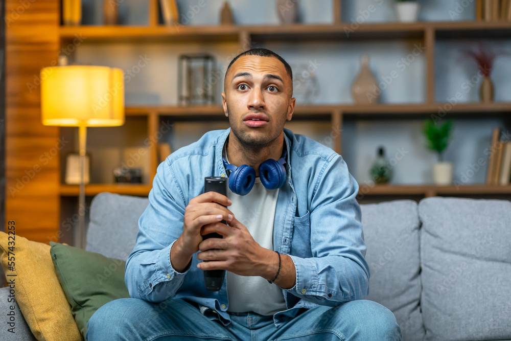 Shocked Black Man With Remote Controller In Hand Sitting On Couch At ...
