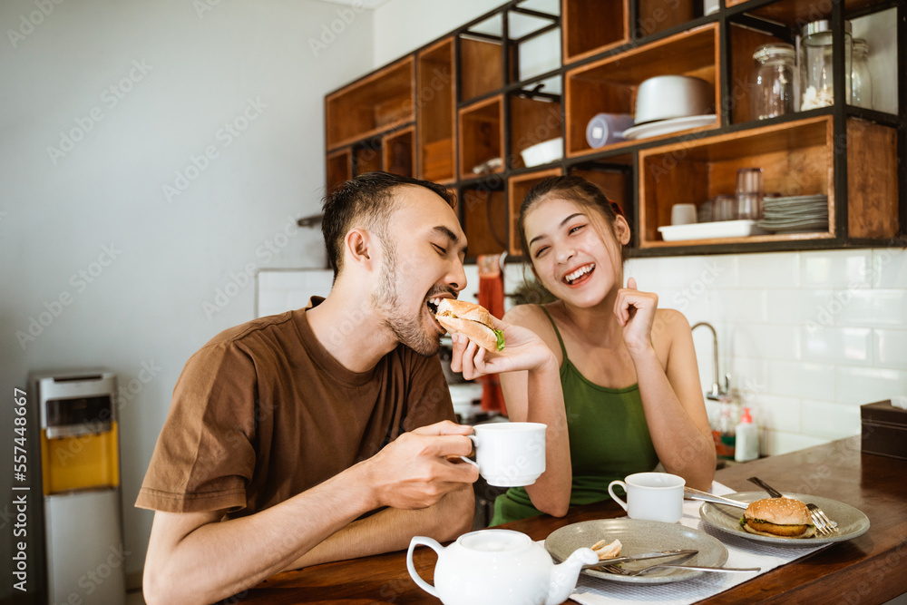 happy asian couple drinking coffee in cups together while feeding each ...