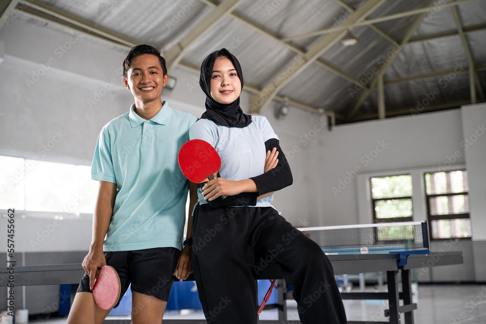 man and woman athlete in hijab standing holding bat with crossed hands ...