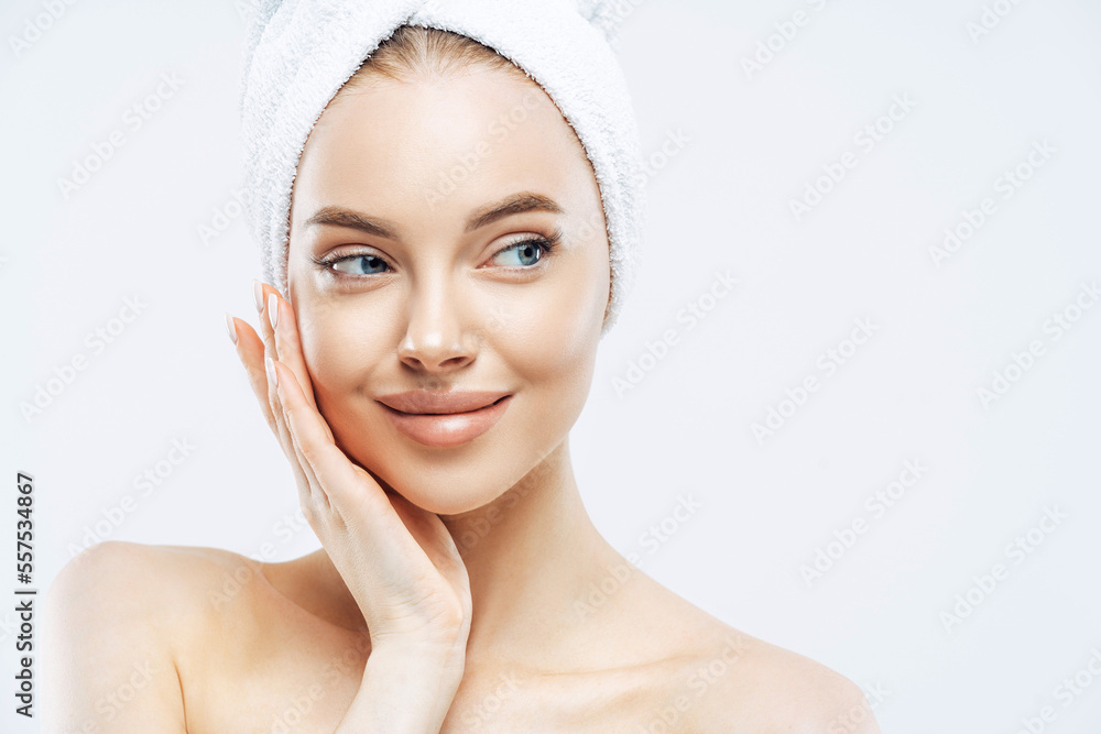 Beautiful female model with makeup, touches cheek, looks aside, has ...