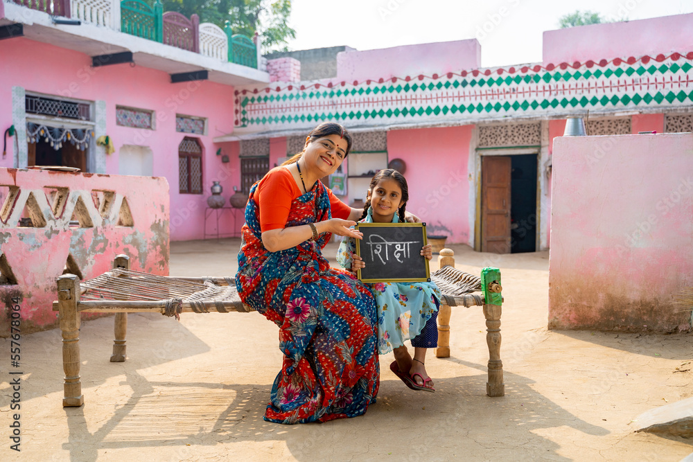 Indian rural woman with her little daughter showing chalk slate ...
