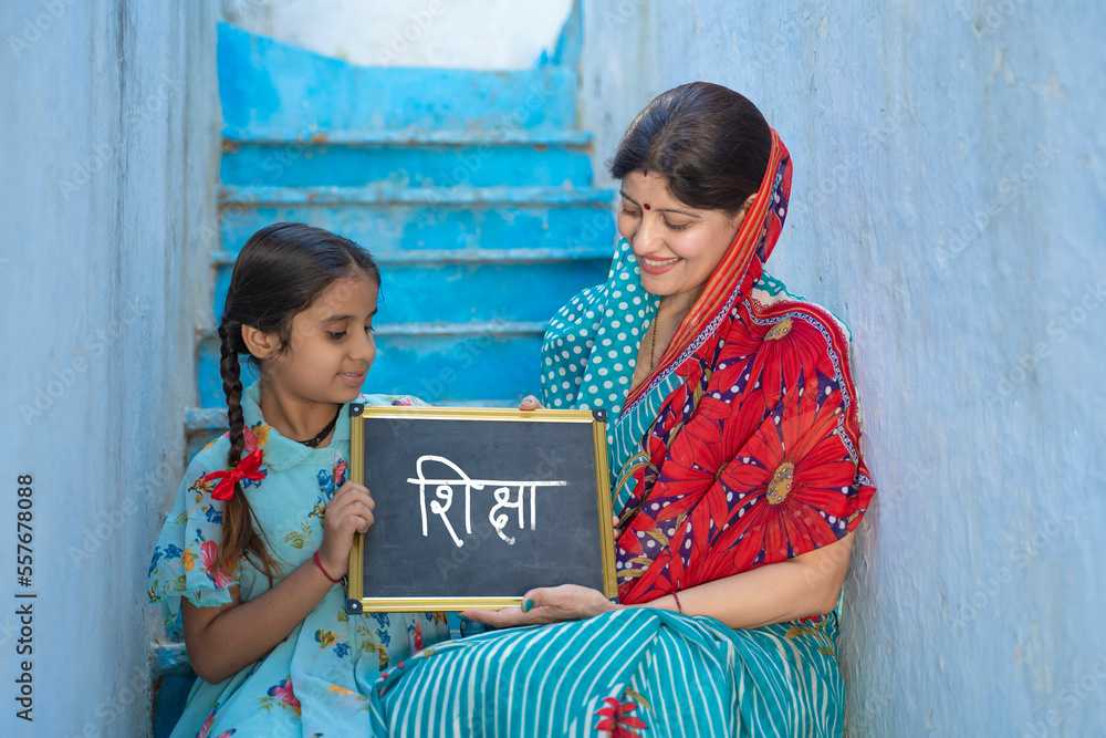 Indian rural woman with her little daughter showing chalk slate ...