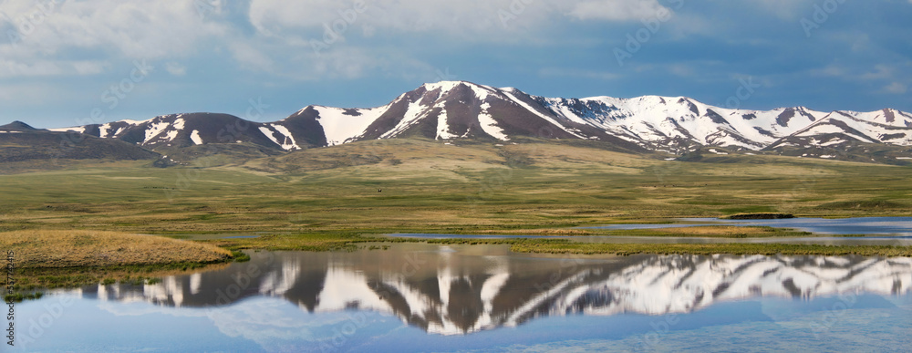 Kyrgyzstan nature green landscape with a reflection lake and vast ...