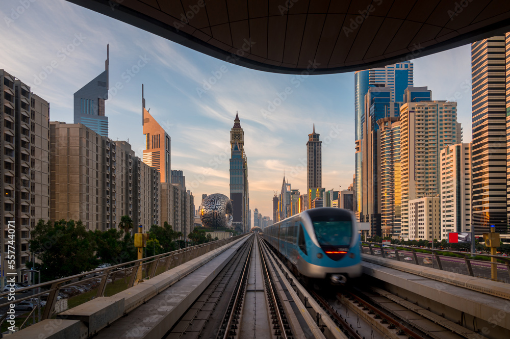 Dubai metro train entering the station with background of high rise ...