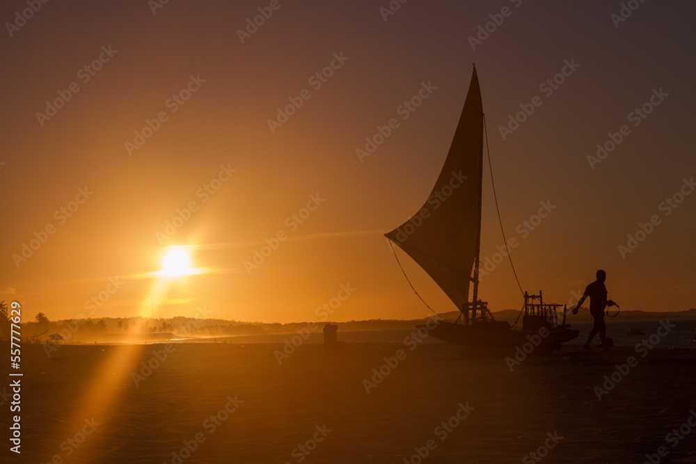 Silueta de persona y barca rustica a vela, sobre la arena y una en un ...