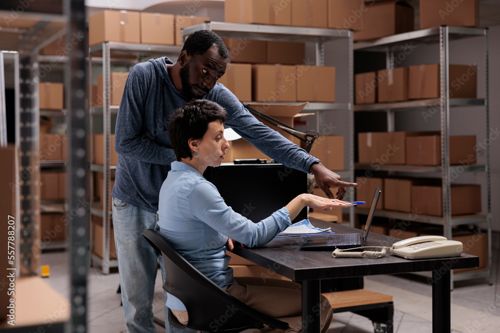 Warehouse employees analyzing delivery checklist on laptop computer ...