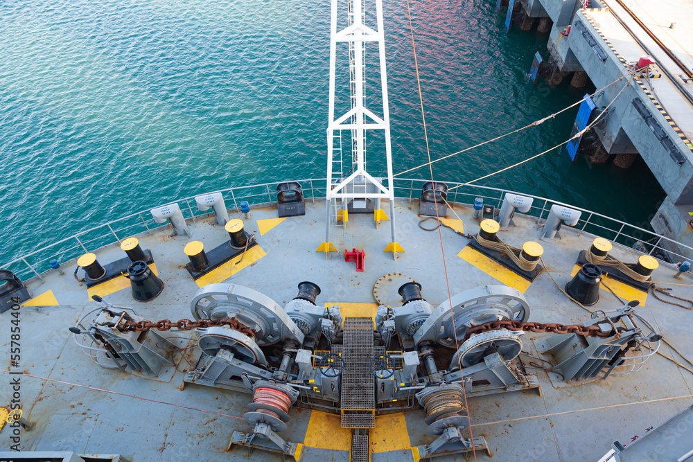 The bow of a cargo ship moored to the pier, with mooring winches on the ...