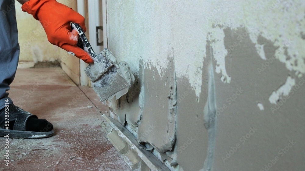 leveling a room wall with a thick layer of plastic putty using a ...