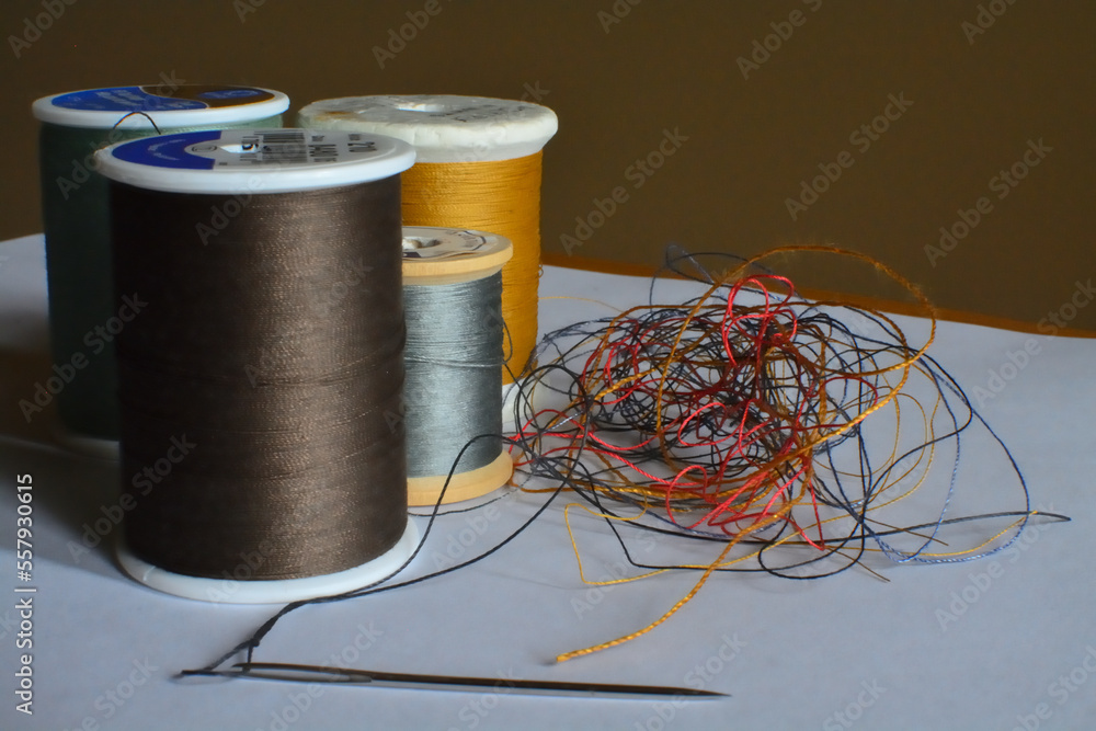 four spools of thread with needle and tangled strands Stock Photo ...