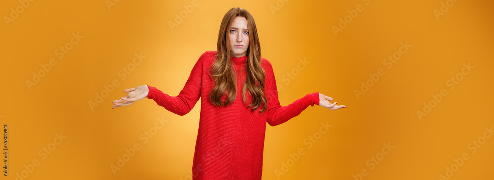 Confused Frustrated And Upset Ginger Woman In Red Sweater Lifting Hands In Dismay Making