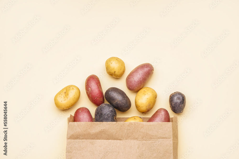 Paper bag with different raw potatoes on color background Stock Photo ...