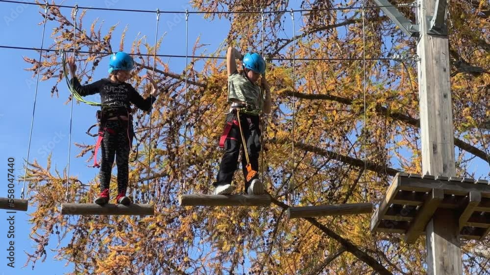 Intrepid kids crossing on suspended rope bridge at wooden structure of ...