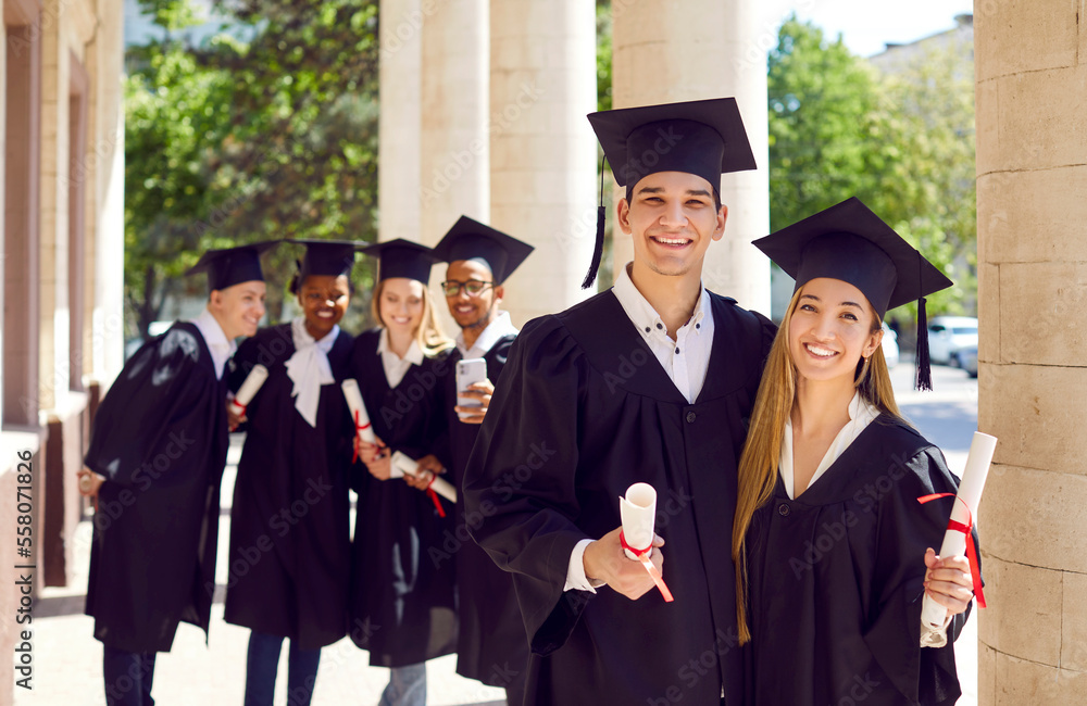 Happy couple students in graduation dresses and hats enjoy graduation ...
