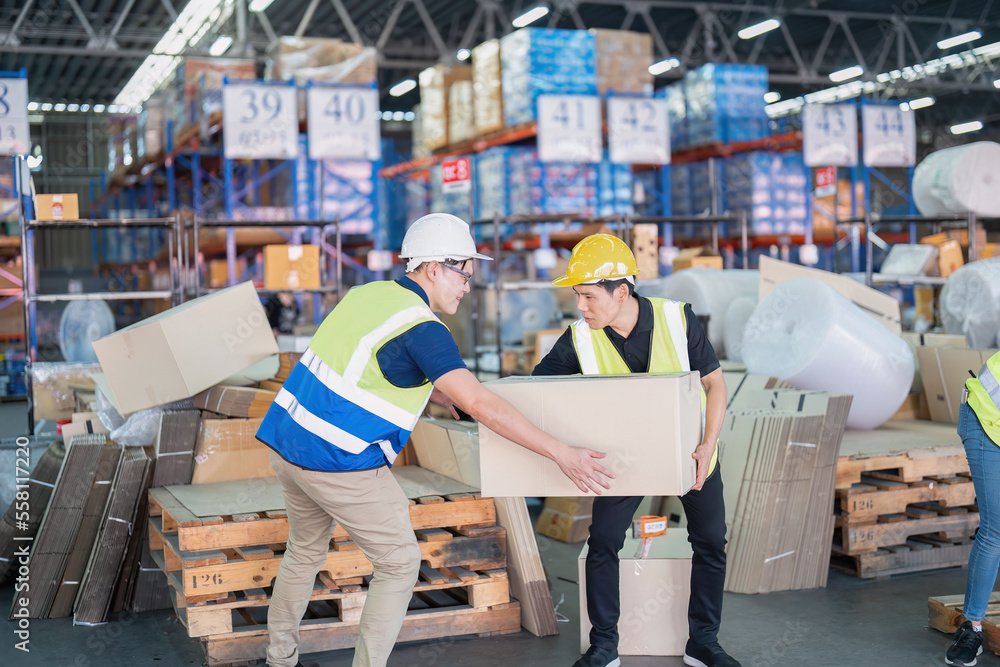 Staff in large storage warehouse together packing goods and carry ...