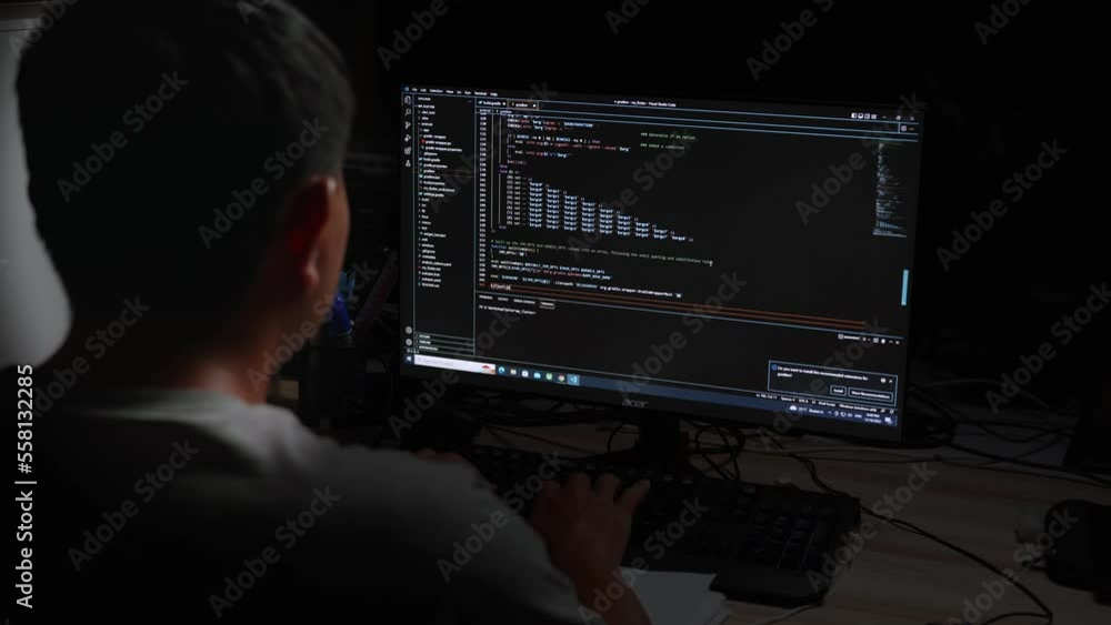 Back view young asian man sitting at desk using computer programming debugging improving binary ...