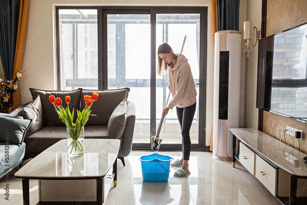 Beautiful young Caucasian blonde housewife cleaning floor in living ...