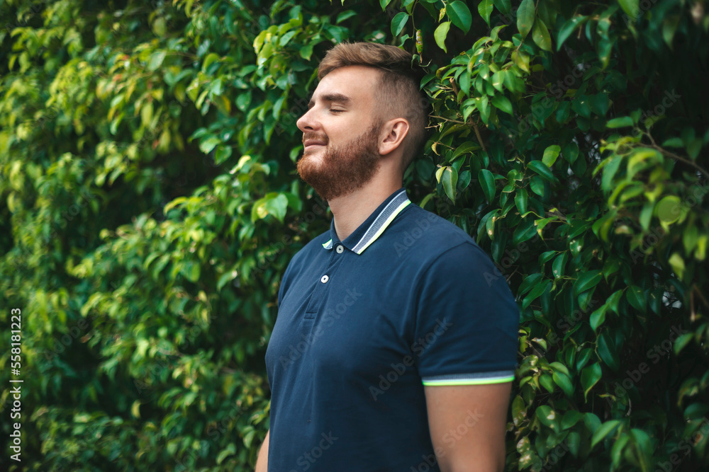 Portrait of a beautiful young bearded man with beard standing on an Ivy ...