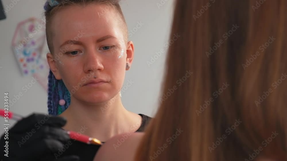 Tattoo artist girl at work. A feminist with dreadlocks gets a tattoo. A ...