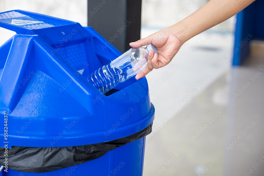 Close up female throwing empty bottle to trash, woman hand throwing empty plastic water bottle ...