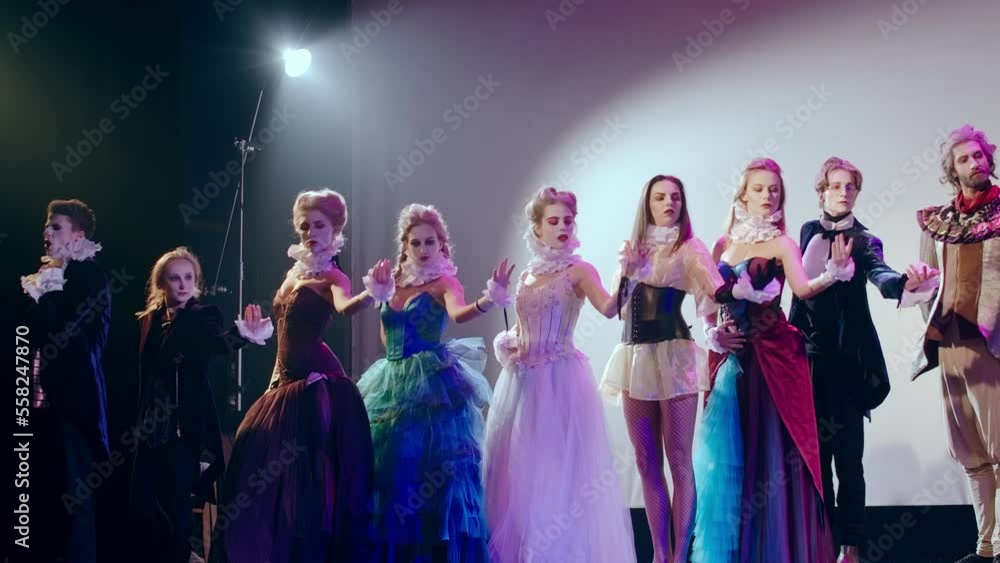 Side view row of actors in retro costumes with neck ruff moving hands ...