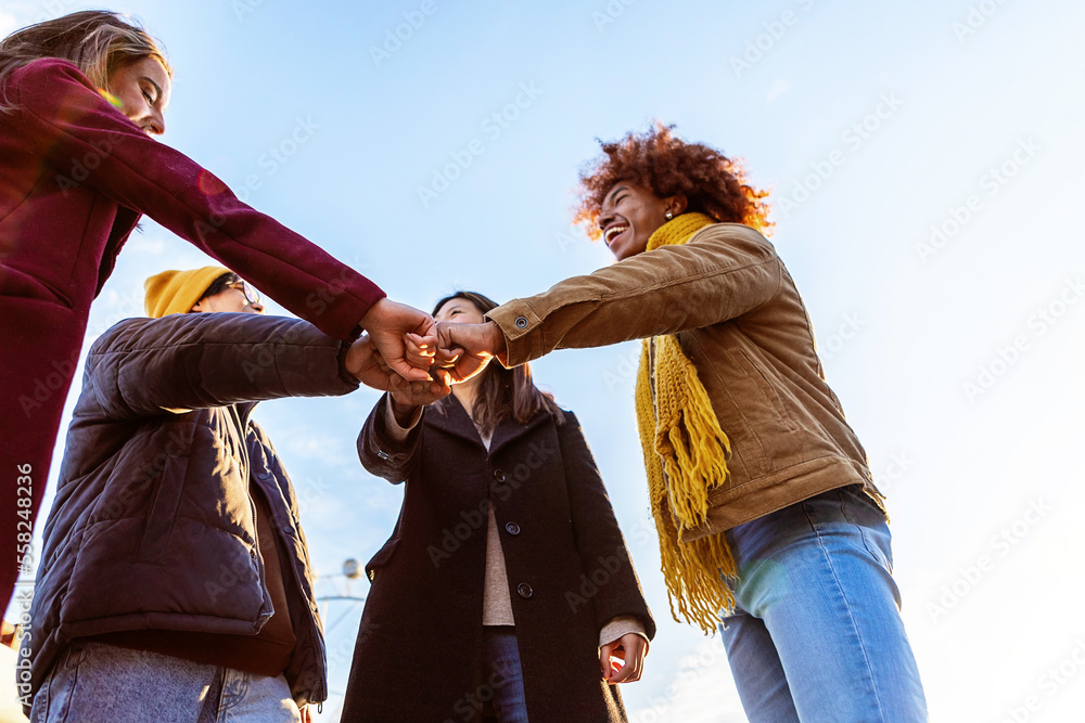 Multiracial group of friends giving fist bump together showing unity ...