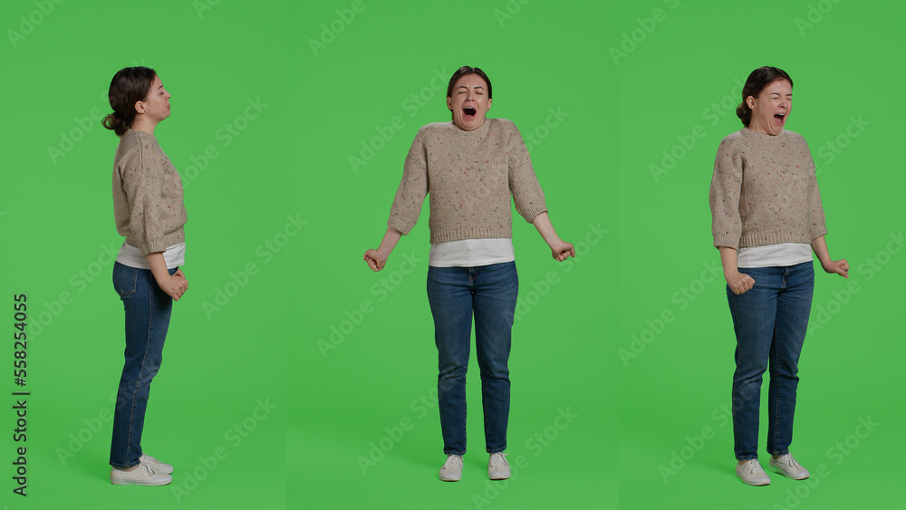 Tired female model yawning on studio camera, posing over green screen ...
