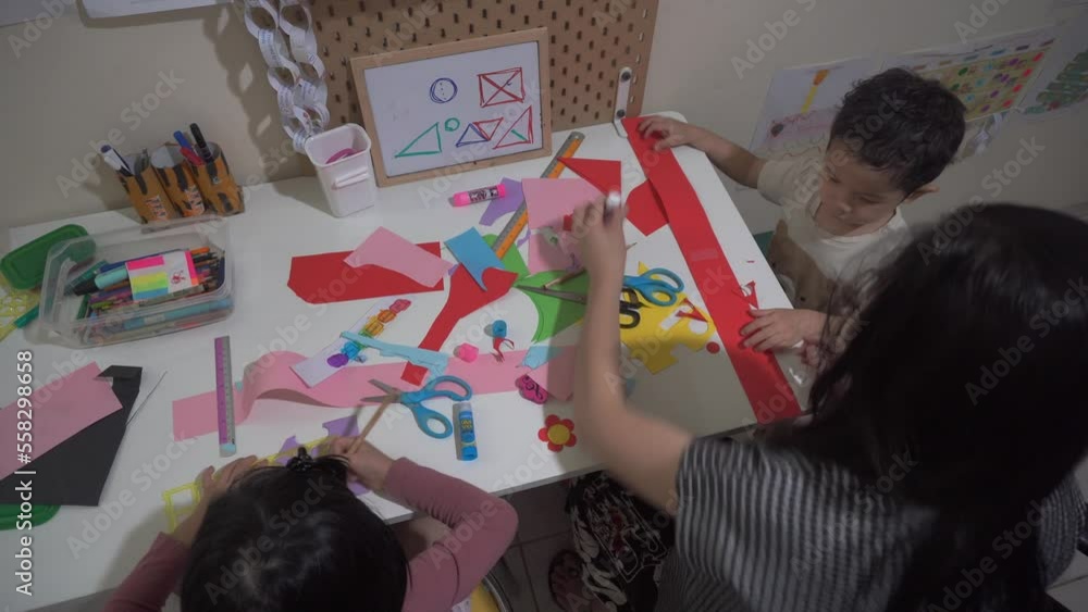 An Asian female teacher, teaching her two students cutting various ...