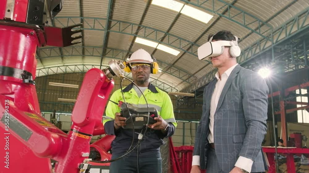 African American engineer demonstrates robotic arm control to customer ...