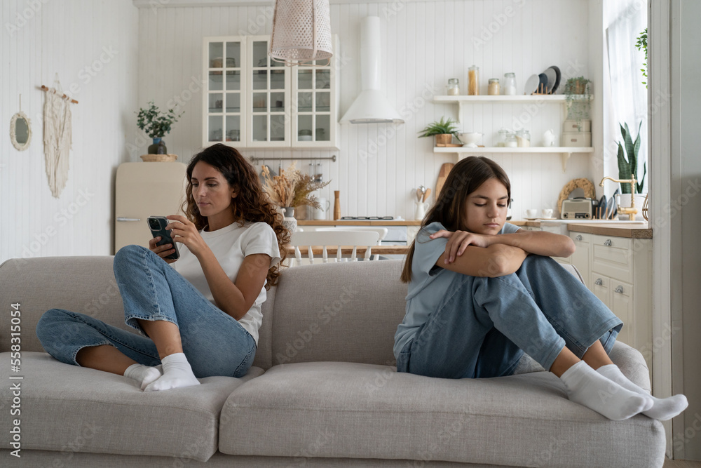 Gadget addicted mother using mobile phone, sitting on sofa with sad ...