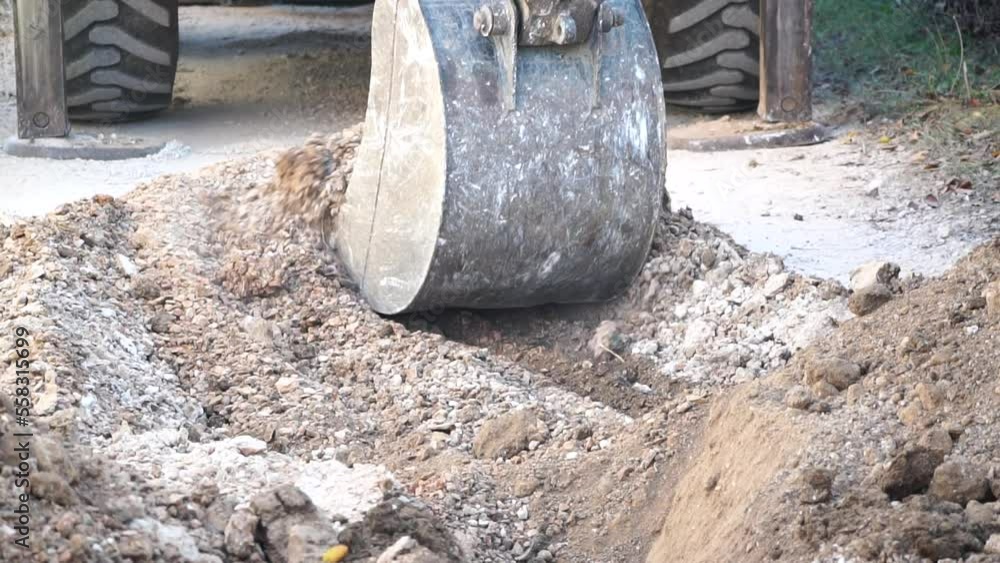 Excavator digs a trench to lay pipes. Close up of an excavator digging ...