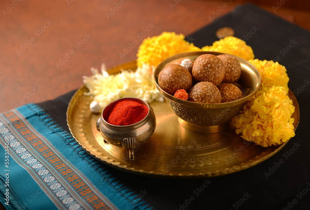 Traditional Indian black color Saari and Til Laddoo in puja thali ...